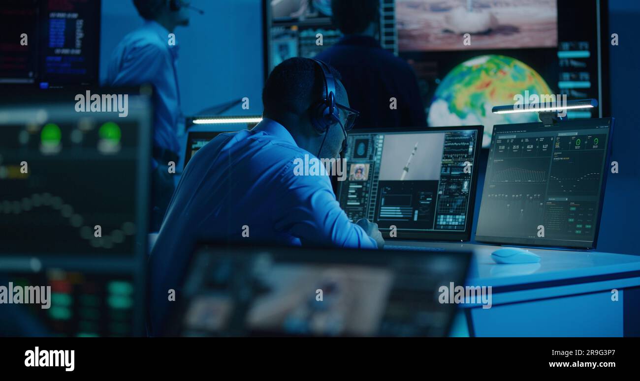 African American flight control employee monitors space mission on ...