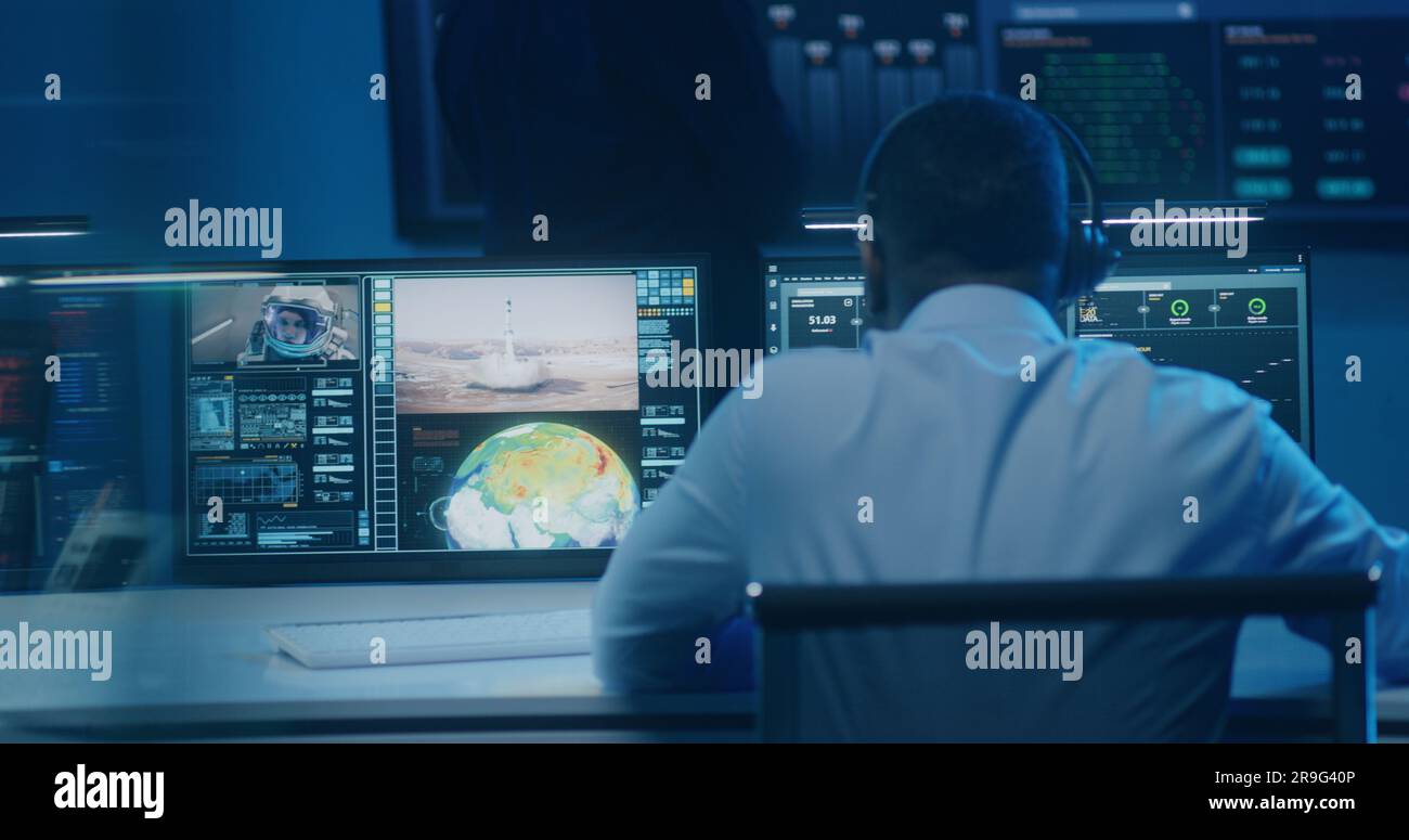 African American flight control employee sits in front of computers ...