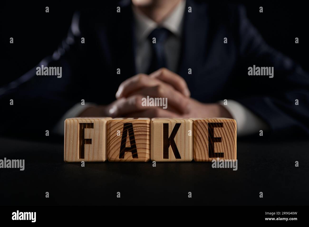 Fake concept, wooden cube on the background of a businessman in a night ...