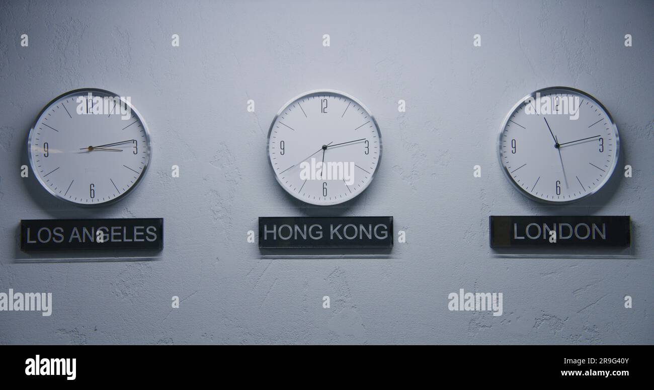 Static shot of white wall clocks with running time pointers illuminated ...