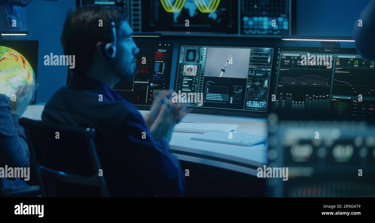 Diverse flight control operators in headsets monitor space mission on ...