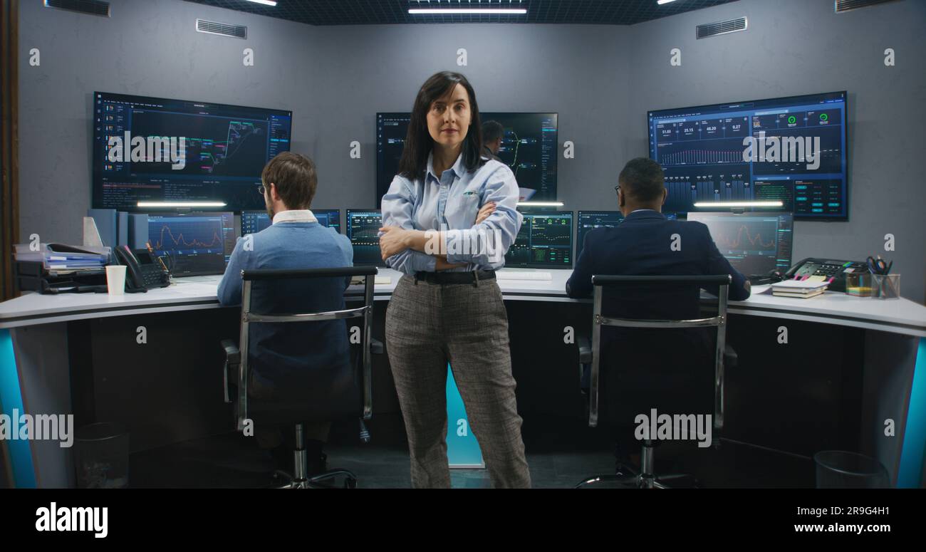 Female big data scientist stands in monitoring room and looks at camera ...