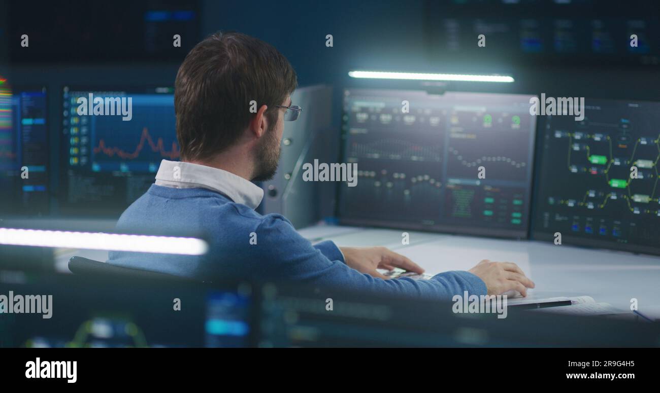 Professional software engineer sits in front of computer with big data server and blockchain ...