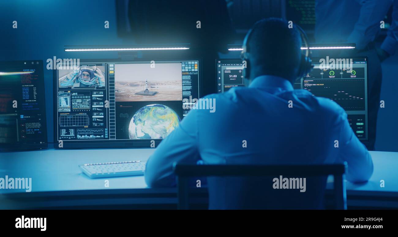 African American flight control employee sits in front of computers ...