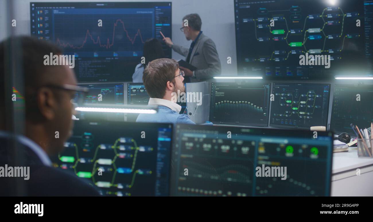 Technical support specialists sit at computers with displayed ...