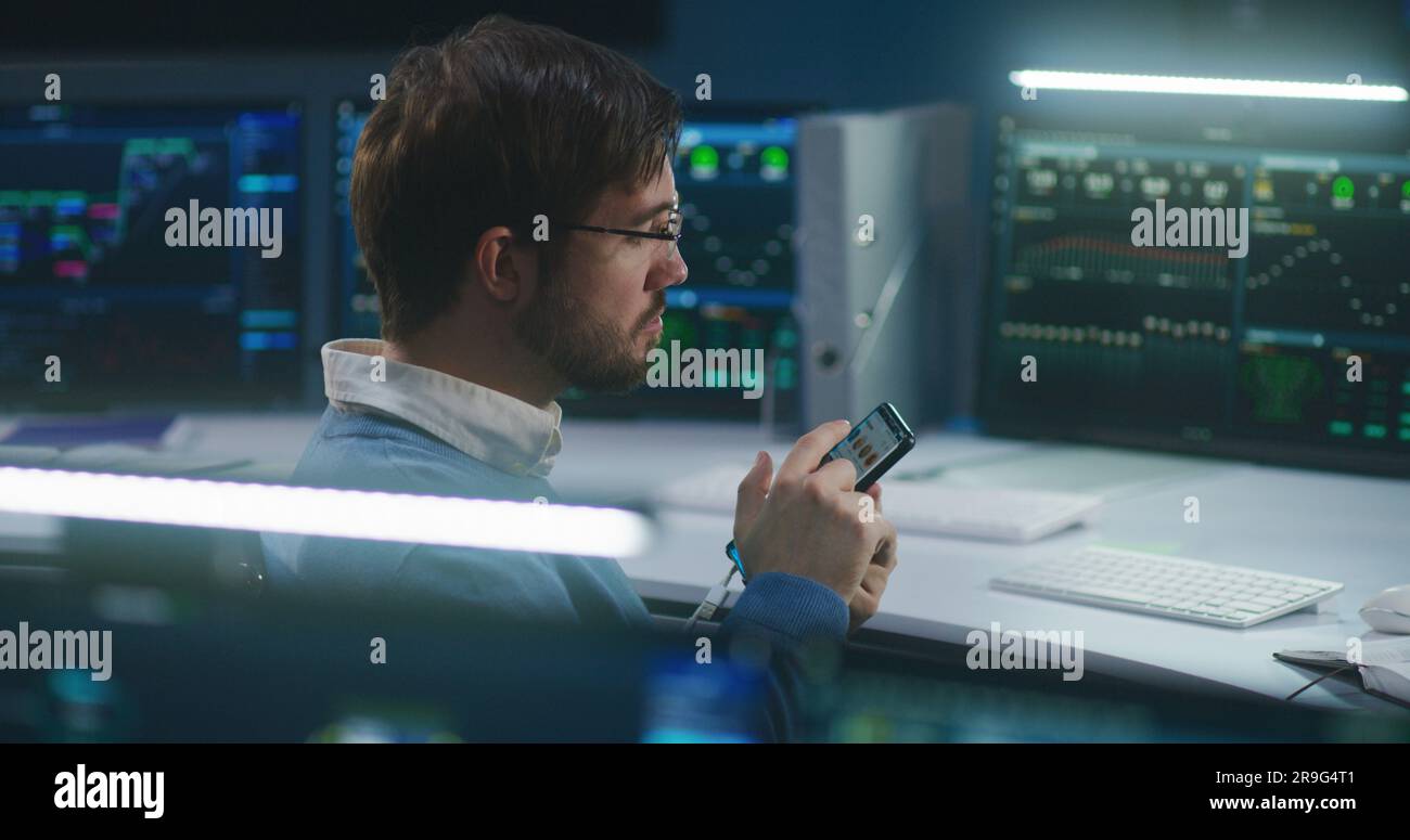 Professional IT technical specialist chats using phone, sits in front of computer with big data ...