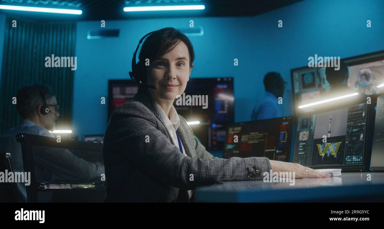 Female flight control worker in headset sits in front of computer ...