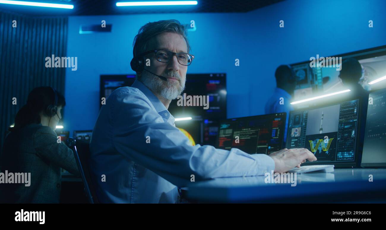 Flight control employee in headset sits in front of computers, monitors ...