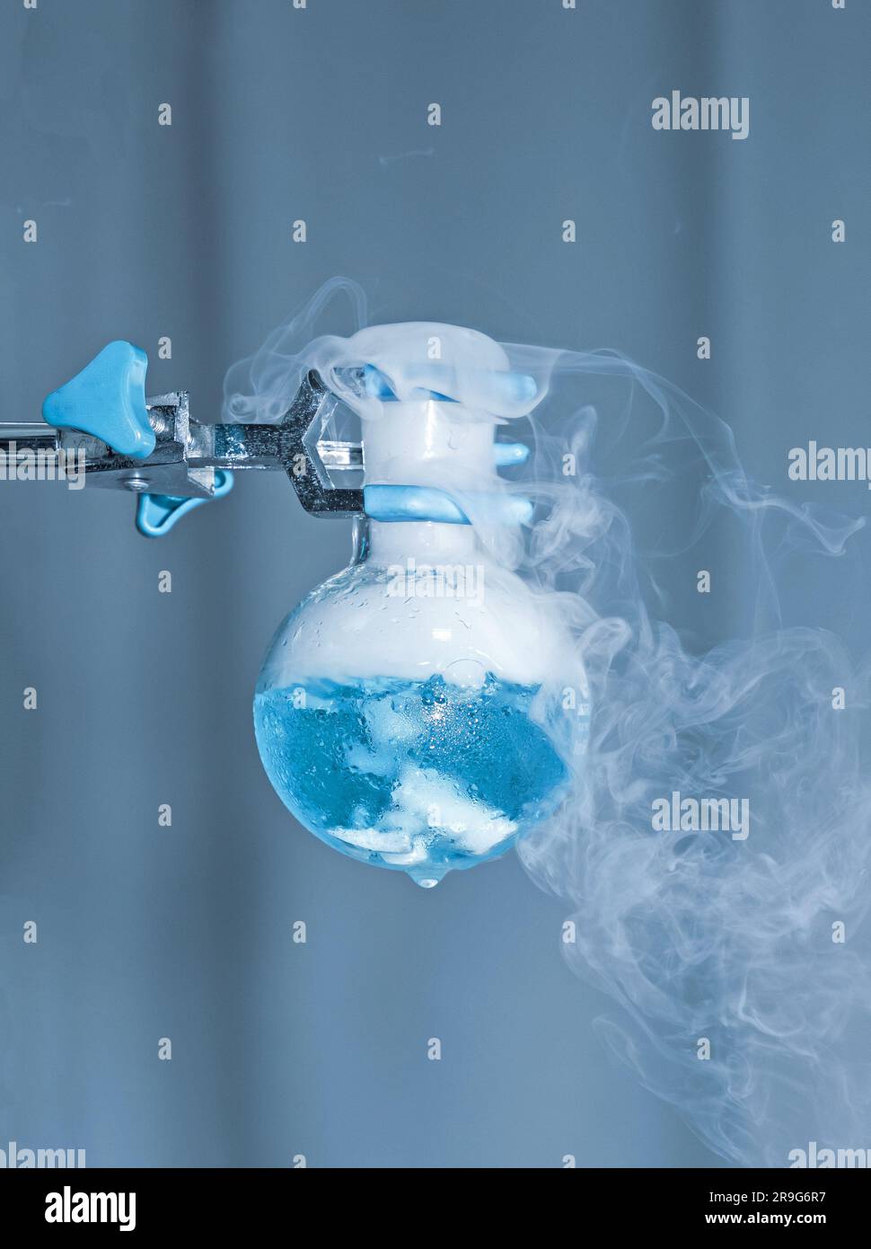 Blue liquid in glass flask with white smoke during experiment in ...