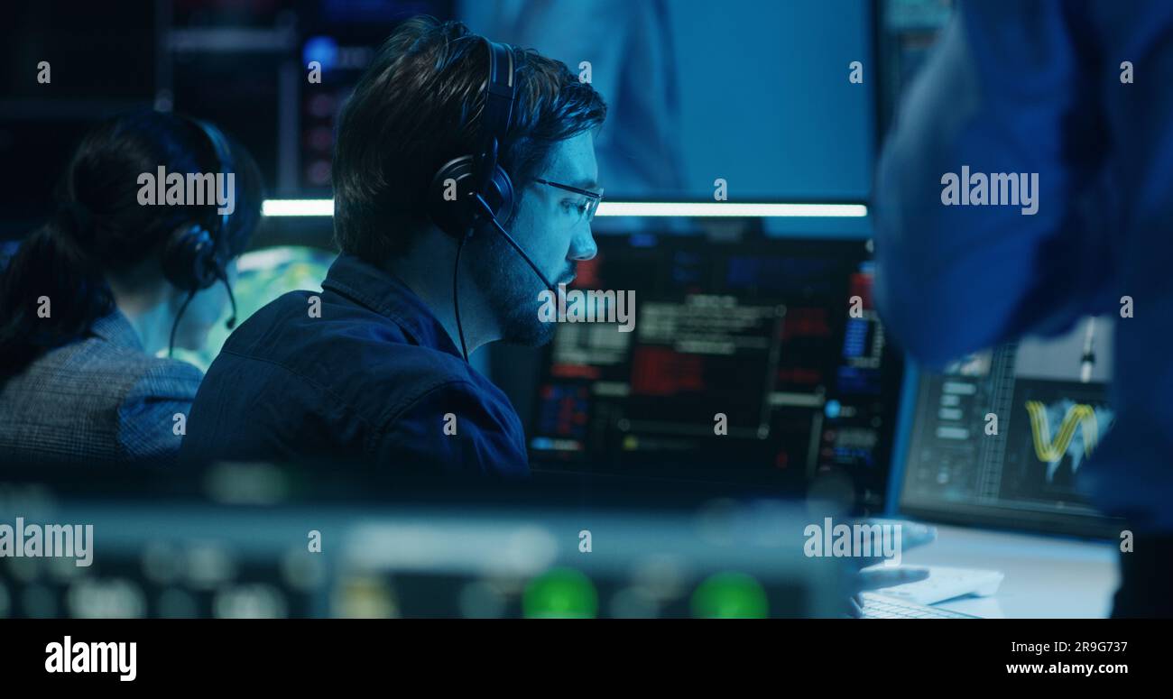 Diverse flight control operators in headsets monitor space mission on ...