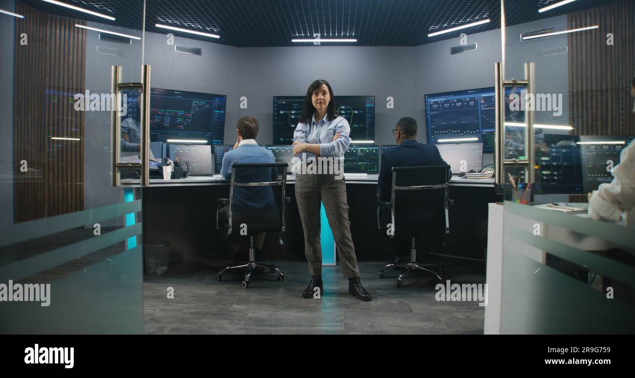 Female big data scientist stands in monitoring room and looks at camera ...