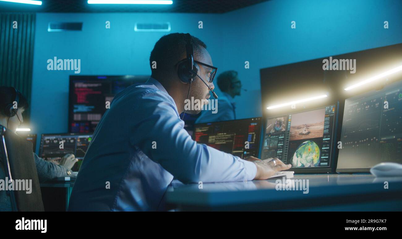 African American flight control employee in headset monitors space ...