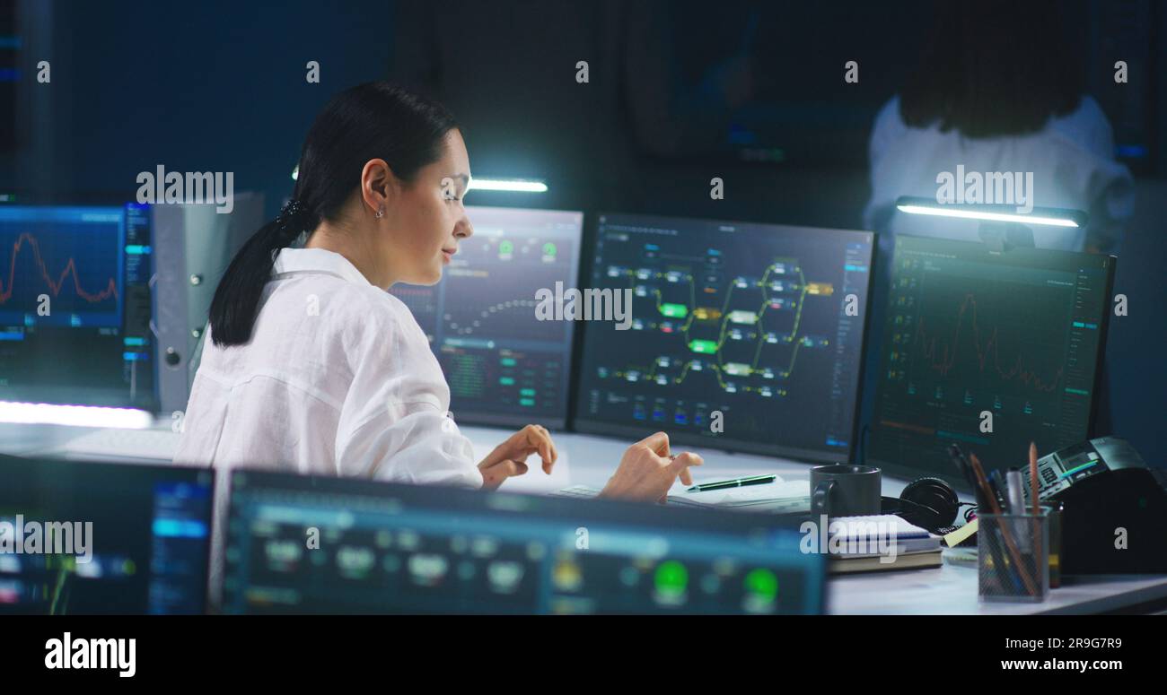 Female IT technical specialist works on computer with data server and ...