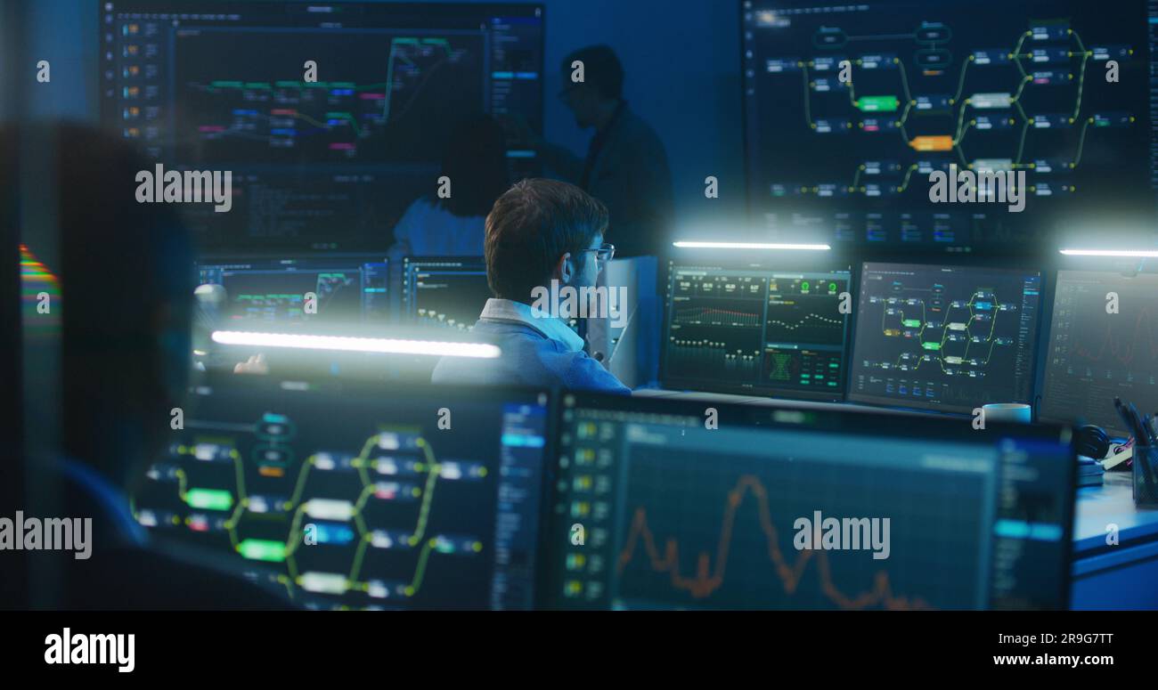 Technical support specialist types keyboard sitting at computer with displayed blockchain ...