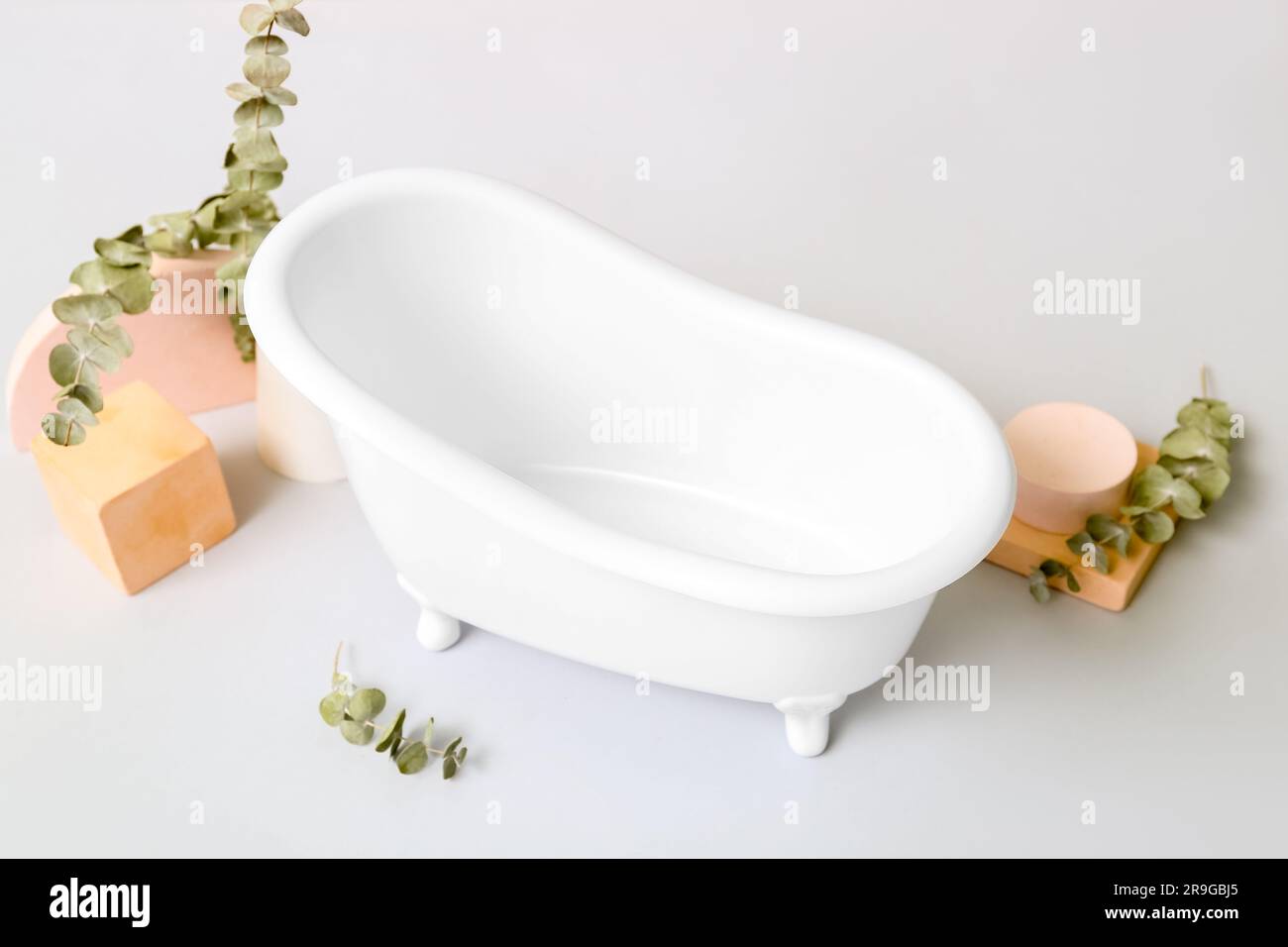 Small bathtub, plaster decor and eucalyptus branches on light ...