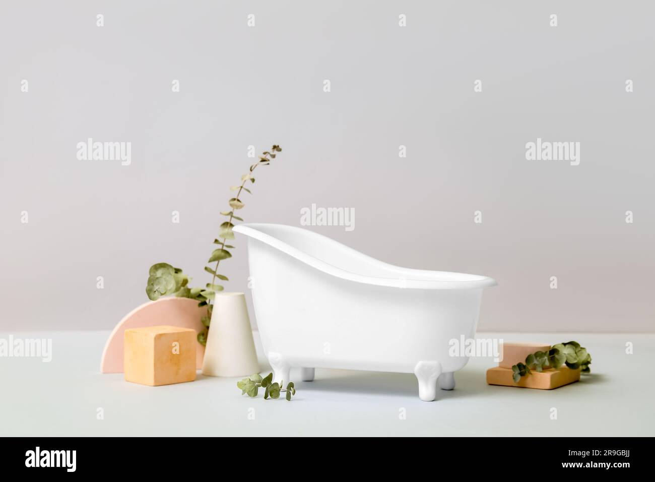 Small bathtub, plaster decor and eucalyptus branches on light ...