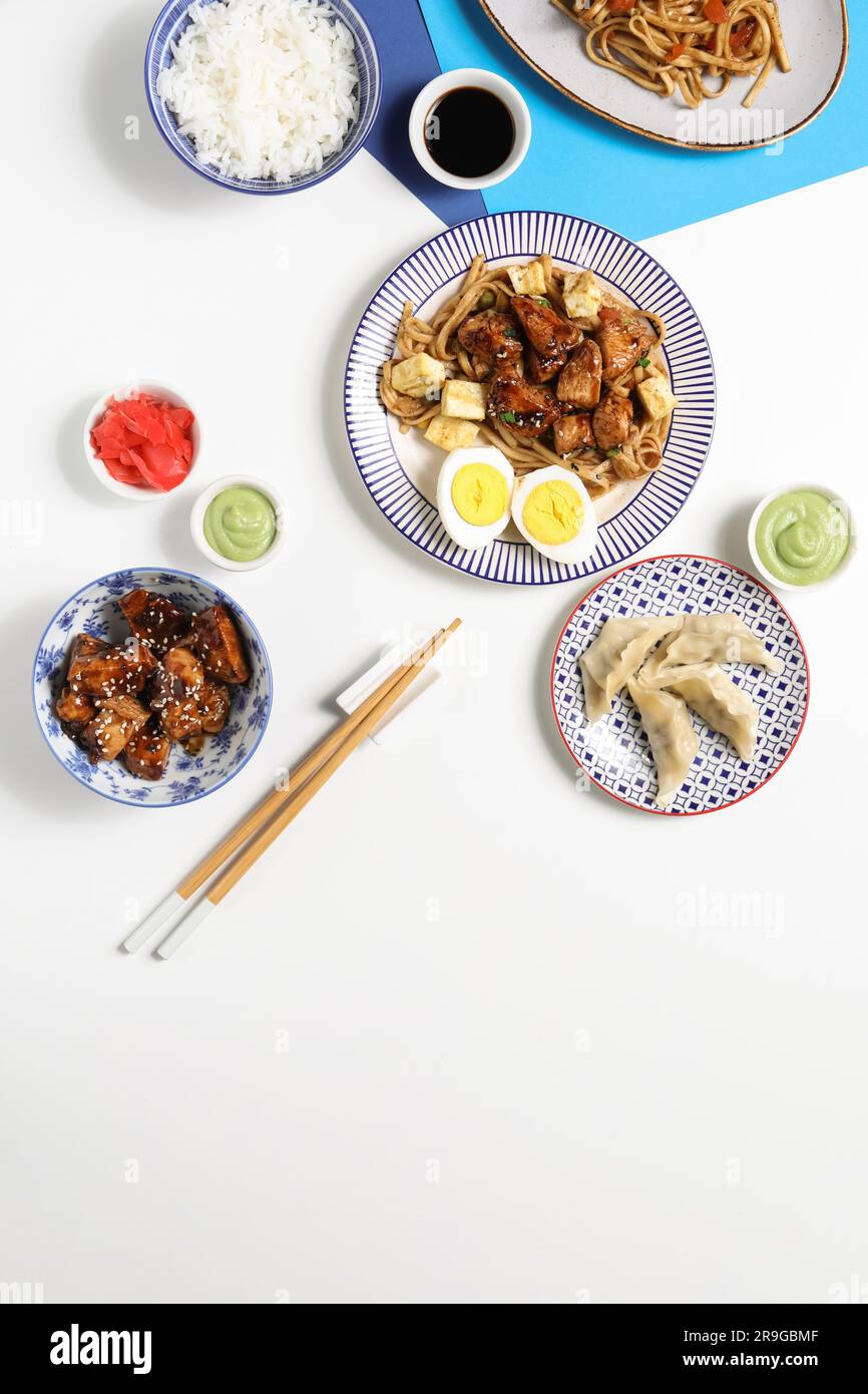 Composition with tasty Chinese dishes and chopsticks on light ...