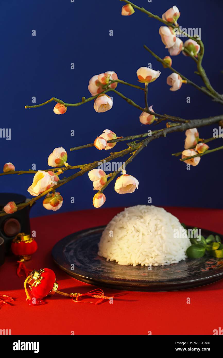 Plate with tasty Chinese rice, lanterns and blooming tree branch on ...