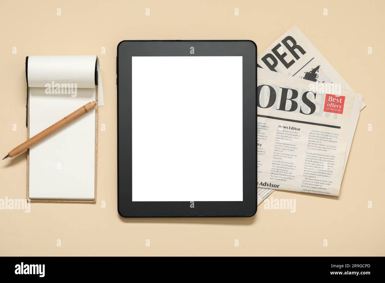 Modern tablet computer, notebook, pen and folded newspaper on beige ...