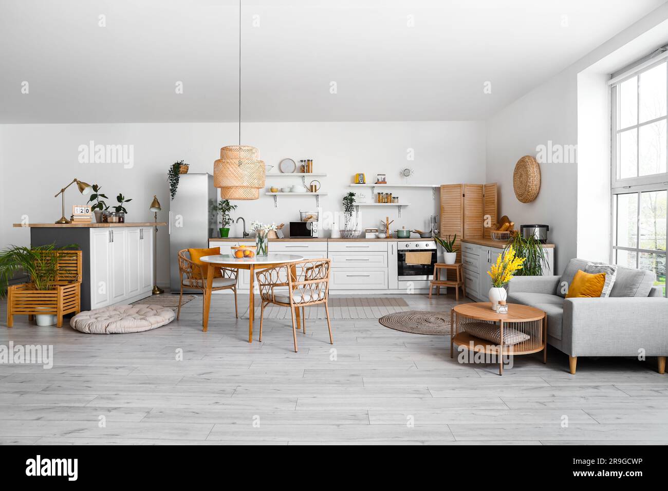 Interior of light kitchen with stylish fridge, counters, sofa and table ...