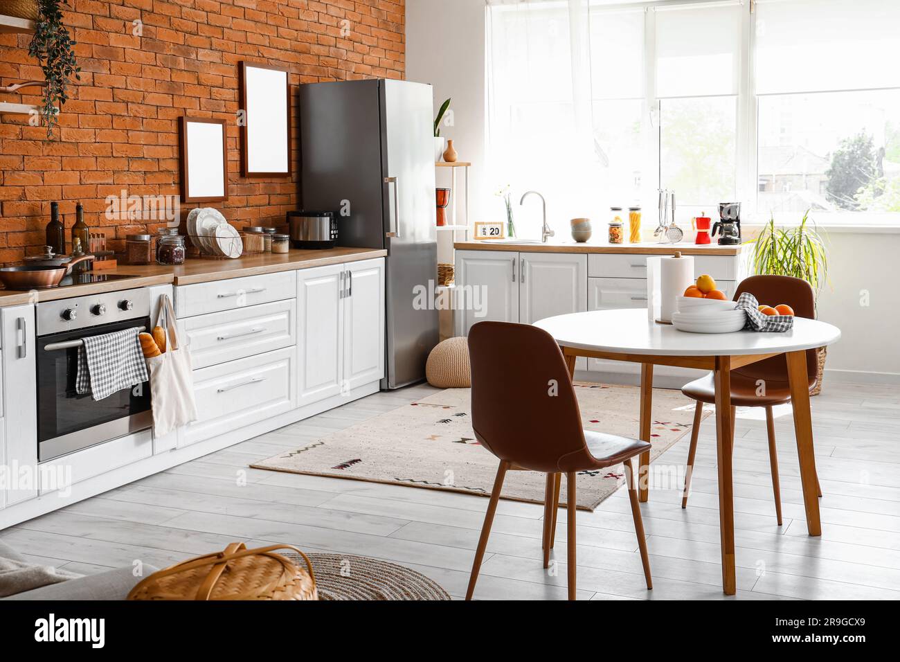 Interior of kitchen with stylish fridge, counters, table and chairs ...