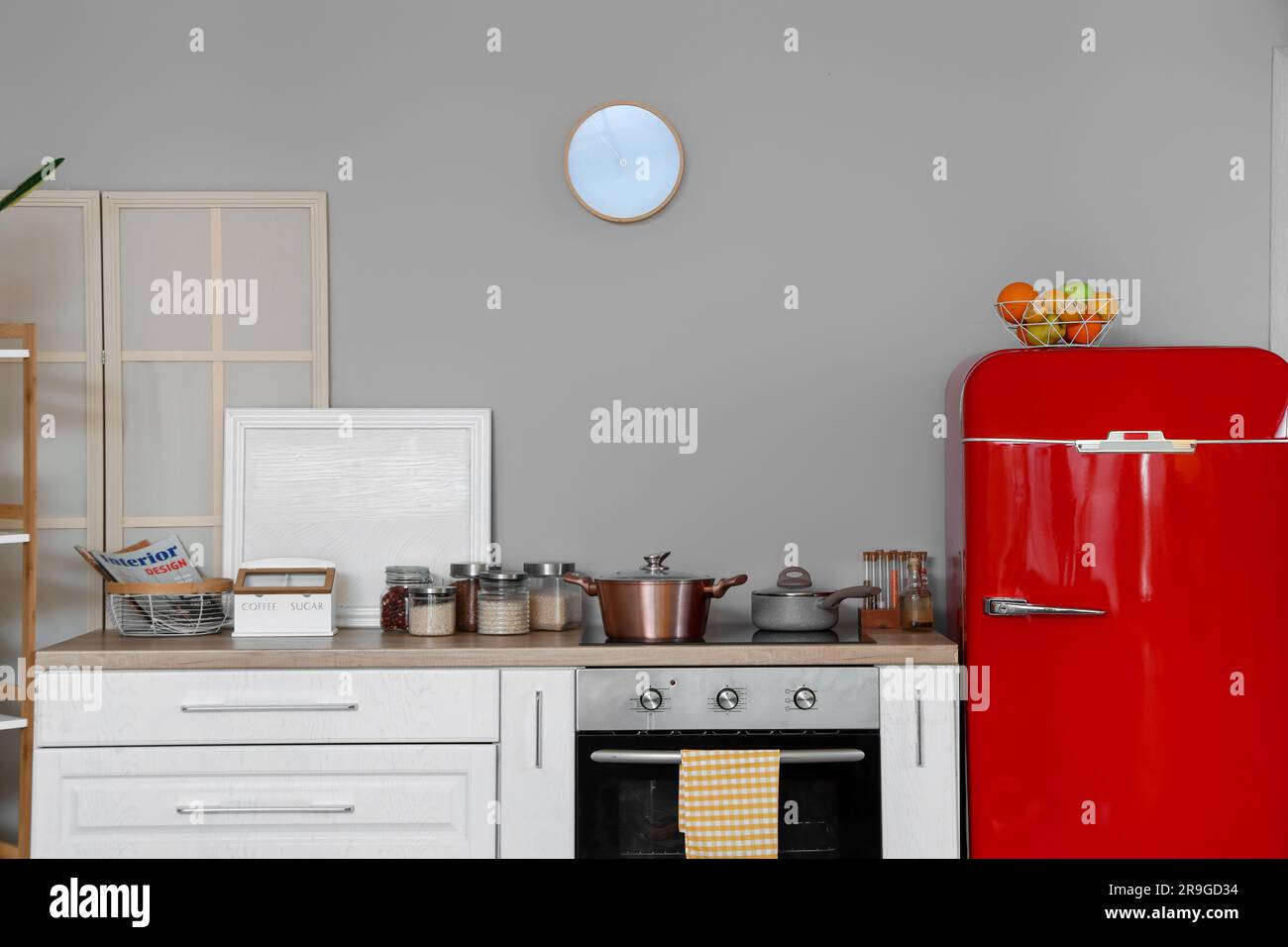 Interior of kitchen with red fridge, counters and clock hanging on ...