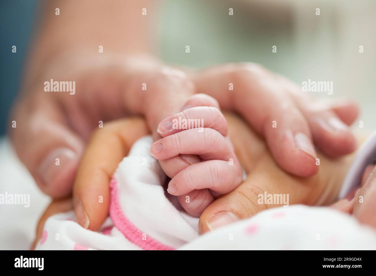 Closeup of a newborn and her parents hands at hospital on the day of ...