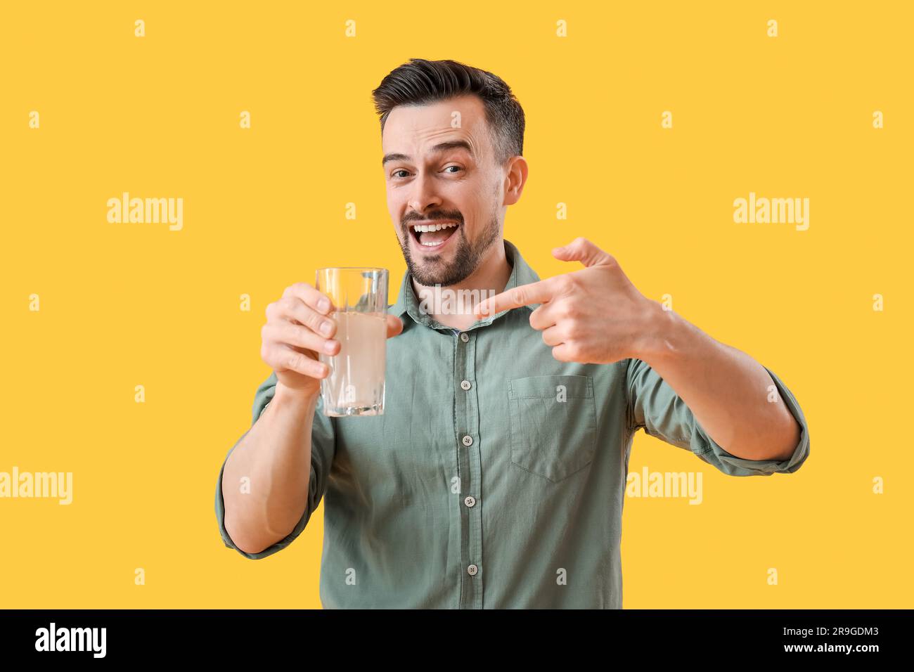 Young man with dissolved tablet and glass of water on yellow background ...