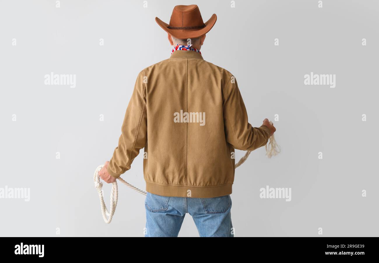 Mature cowboy with lasso on light background, back view Stock Photo - Alamy