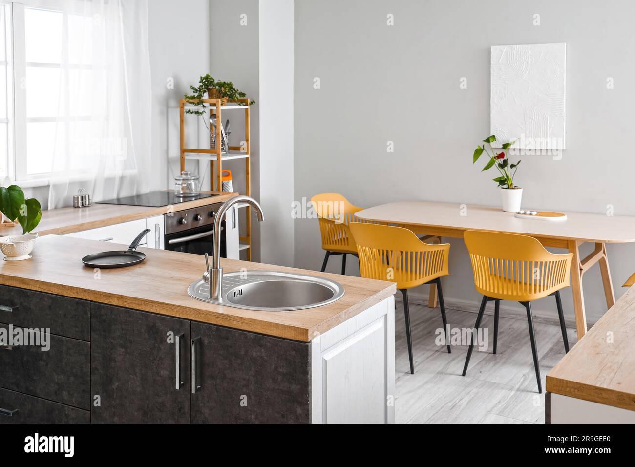 Interior of light kitchen with dining table and sink on wooden ...
