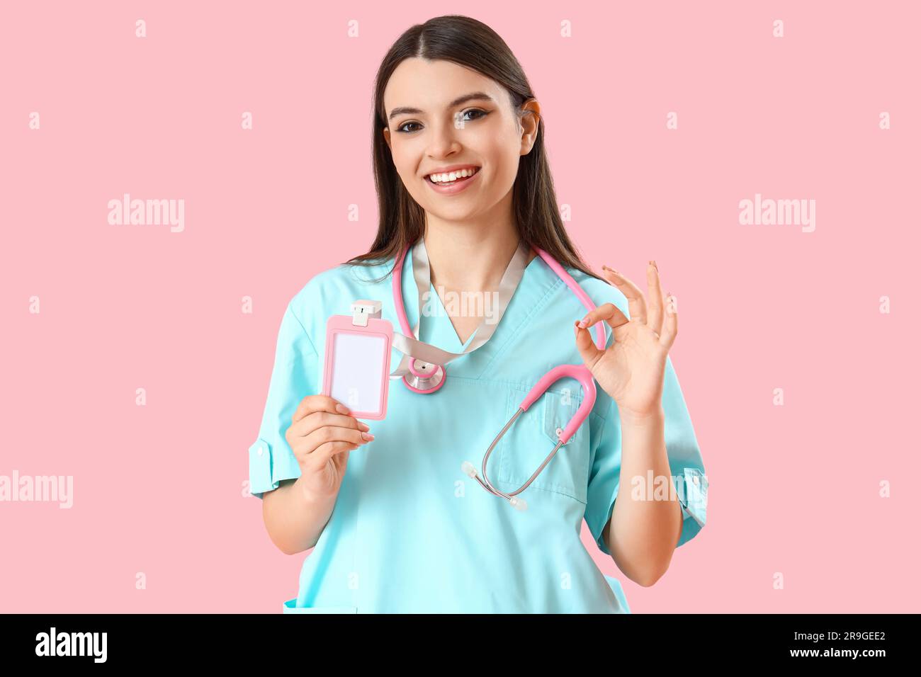 Female medical intern with badge showing OK on pink background Stock ...