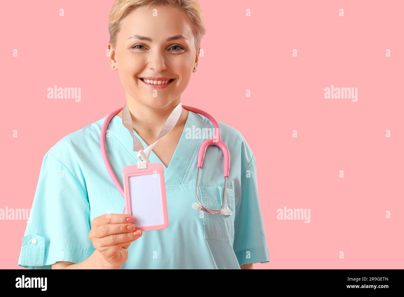 Female medical intern with badge on pink background, closeup Stock ...