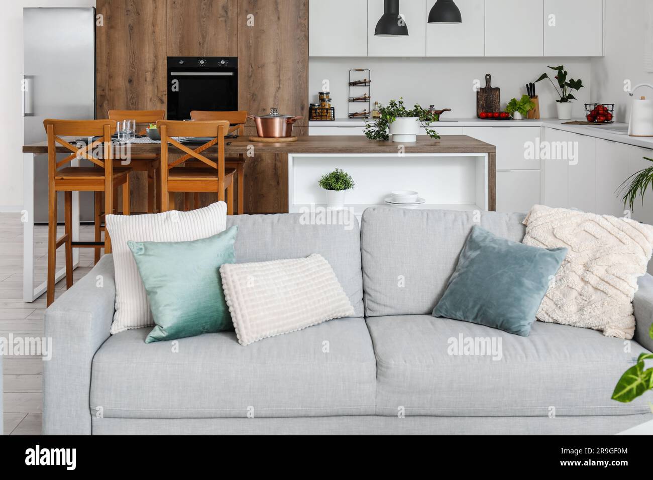 Interior of light open space kitchen with cozy grey sofa and island ...