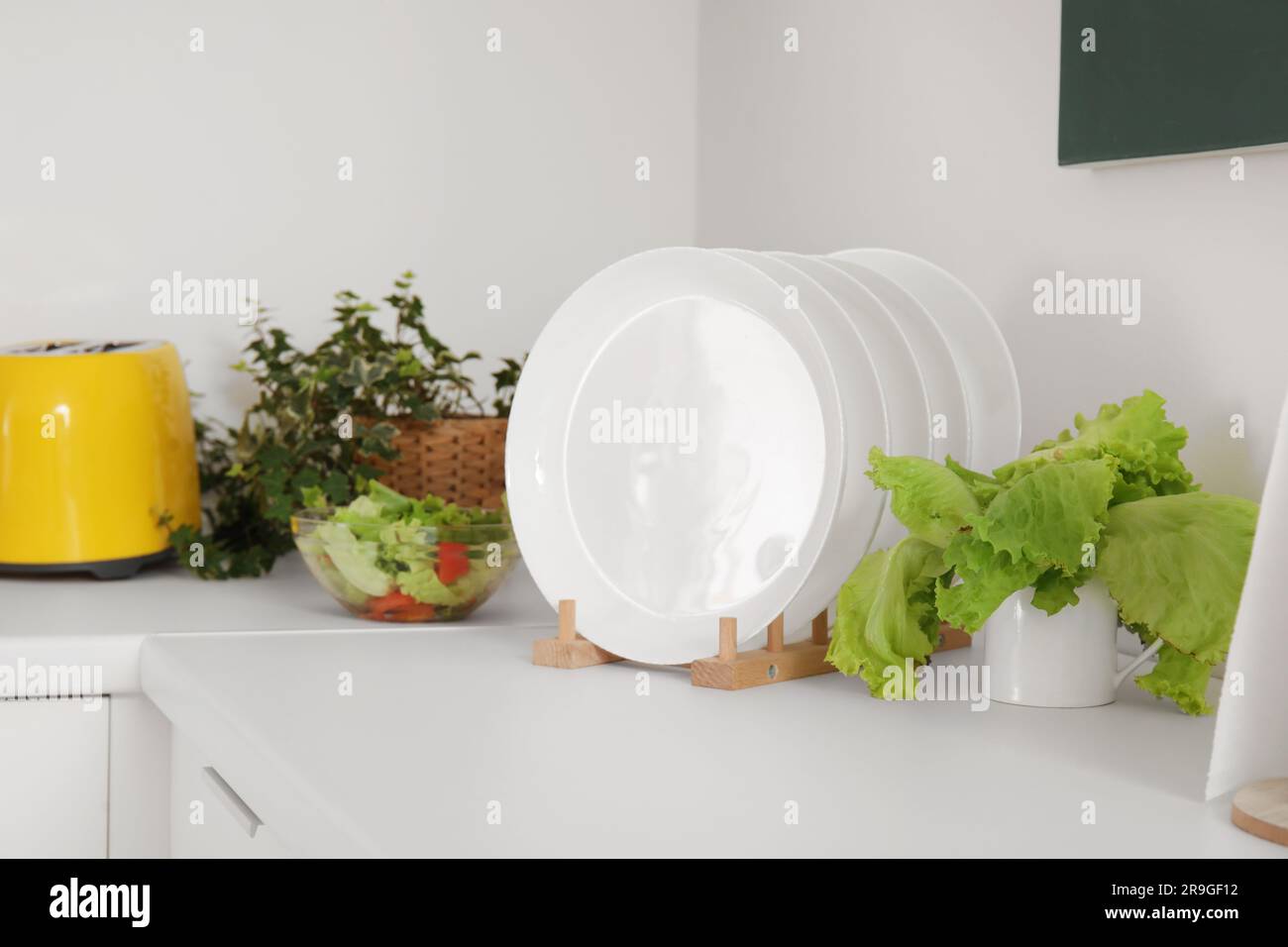 White kitchen counter with plate rack, lettuce and toaster Stock Photo ...