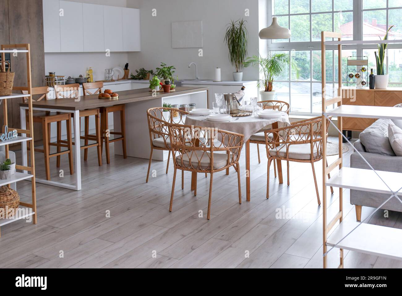 Interior of light open space kitchen with served dining table, island ...