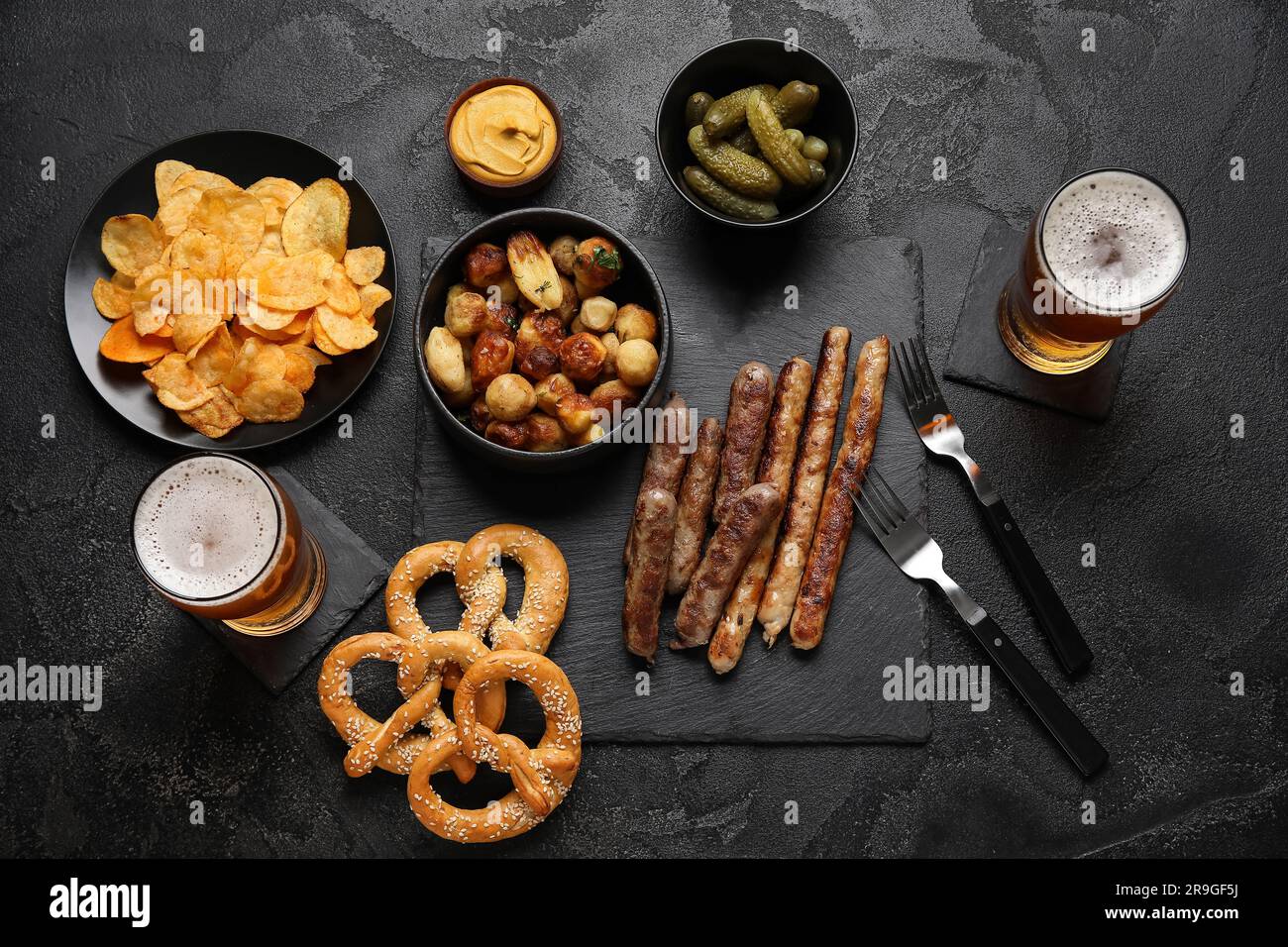 Glasses of cold beer and different snacks on black background ...