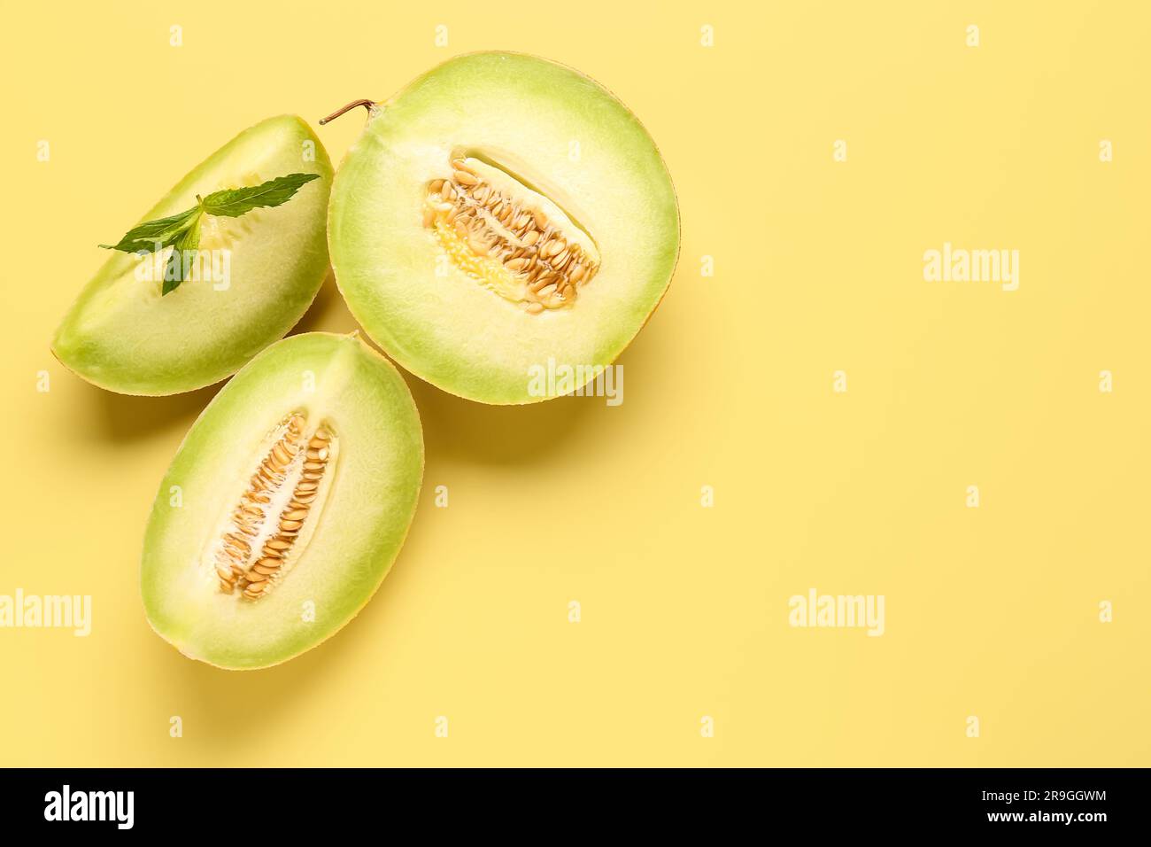 Half of sweet melon with pieces and mint on yellow background Stock ...