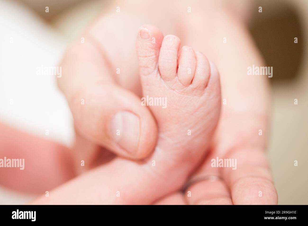 Closeup of a newborn foot and her father hands at hospital on the day ...