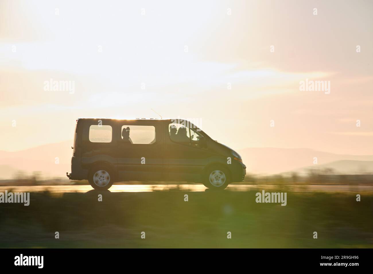 Passenger van driving fast on intercity road at sunset. Highway traffic ...