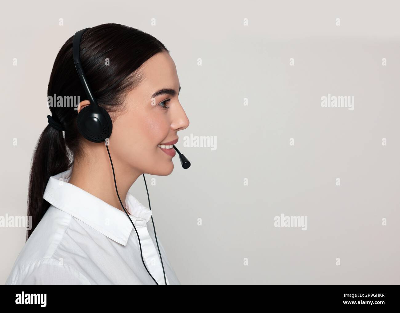 Hotline operator with modern headset on light grey background, space ...