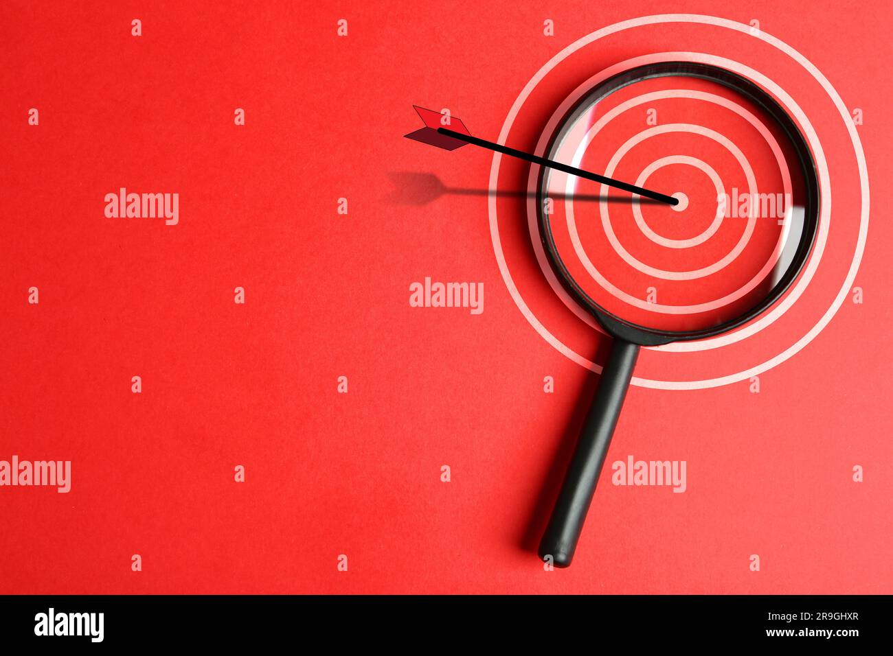 Magnifying glass with illustration of target and arrow on red ...