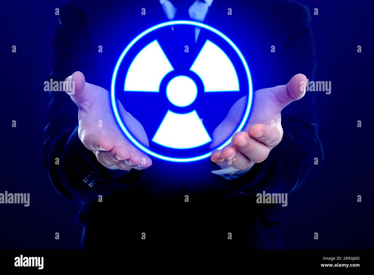 Man holding glowing radiation warning symbol on dark blue background ...