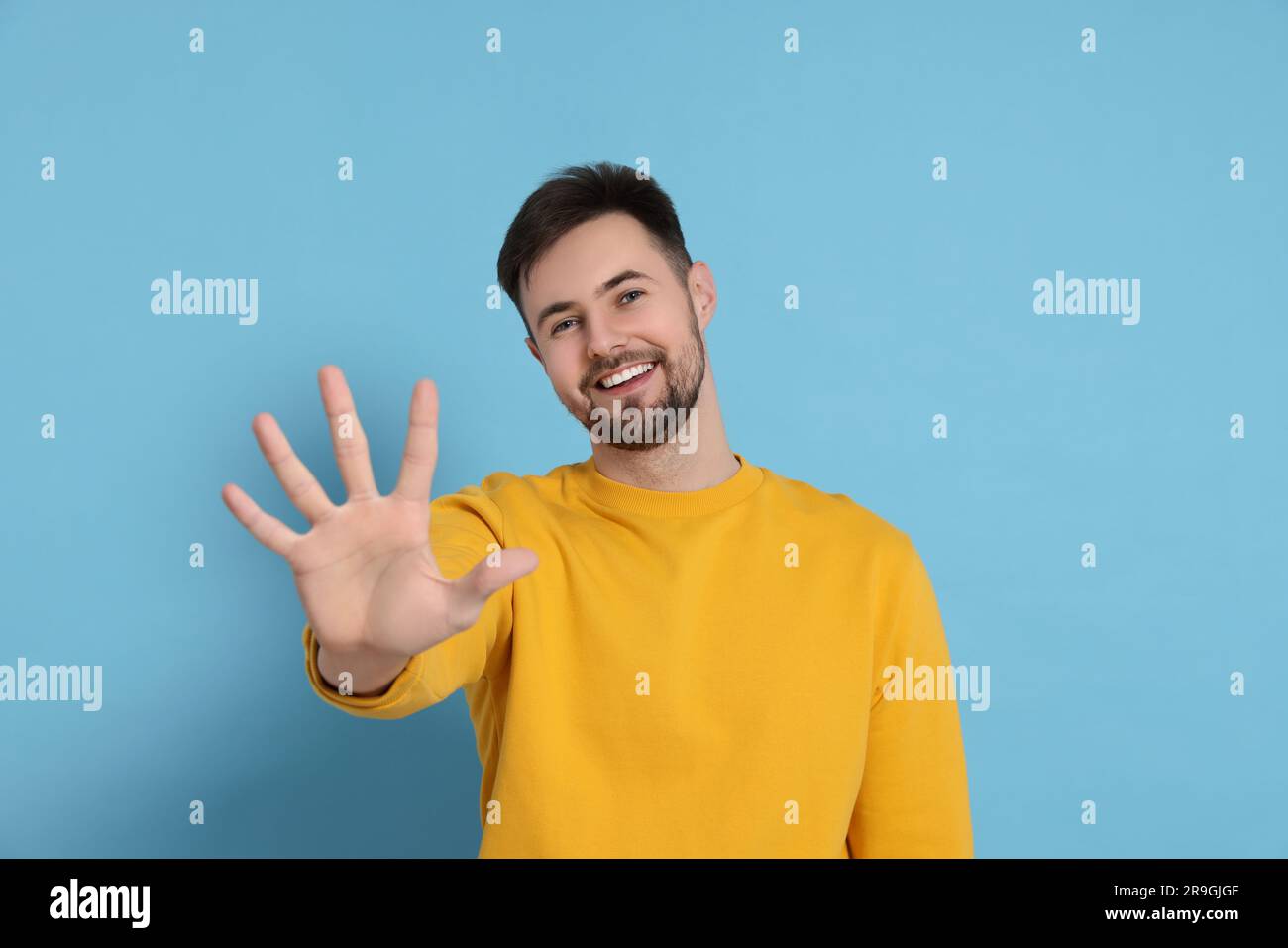 Man giving high five on light blue background Stock Photo - Alamy