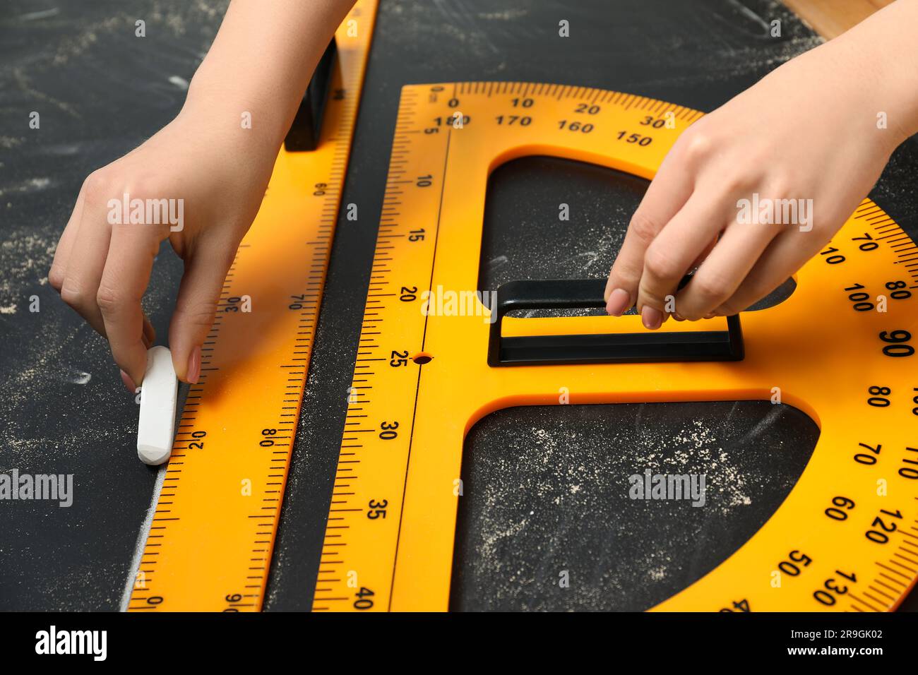 Woman drawing with chalk, ruler and protractor on blackboard, closeup ...