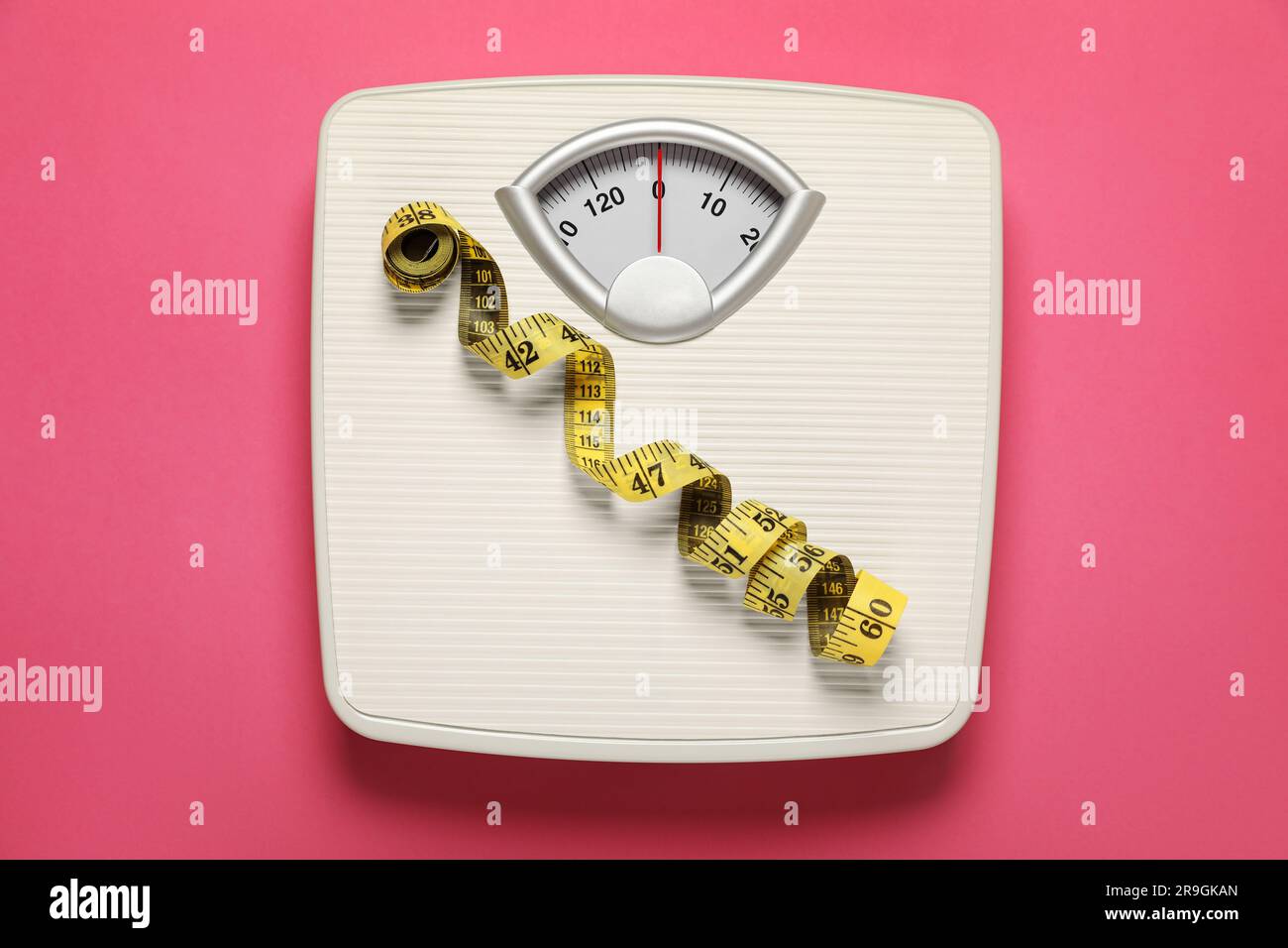 Weigh scales and measuring tape on pink background, top view ...