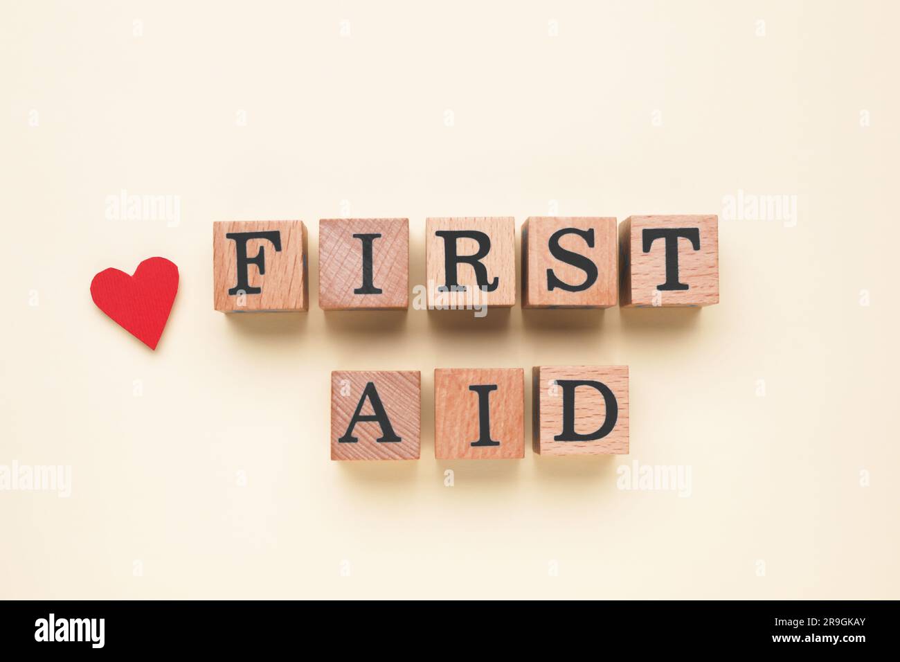 Words First Aid made of wooden cubes and cardboard heart on beige ...