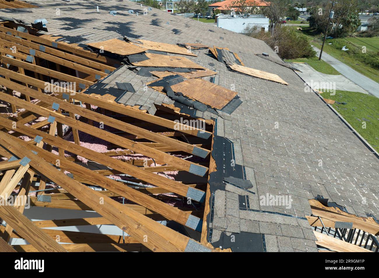 Wind damaged house roof with missing asphalt shingles after hurricane ...