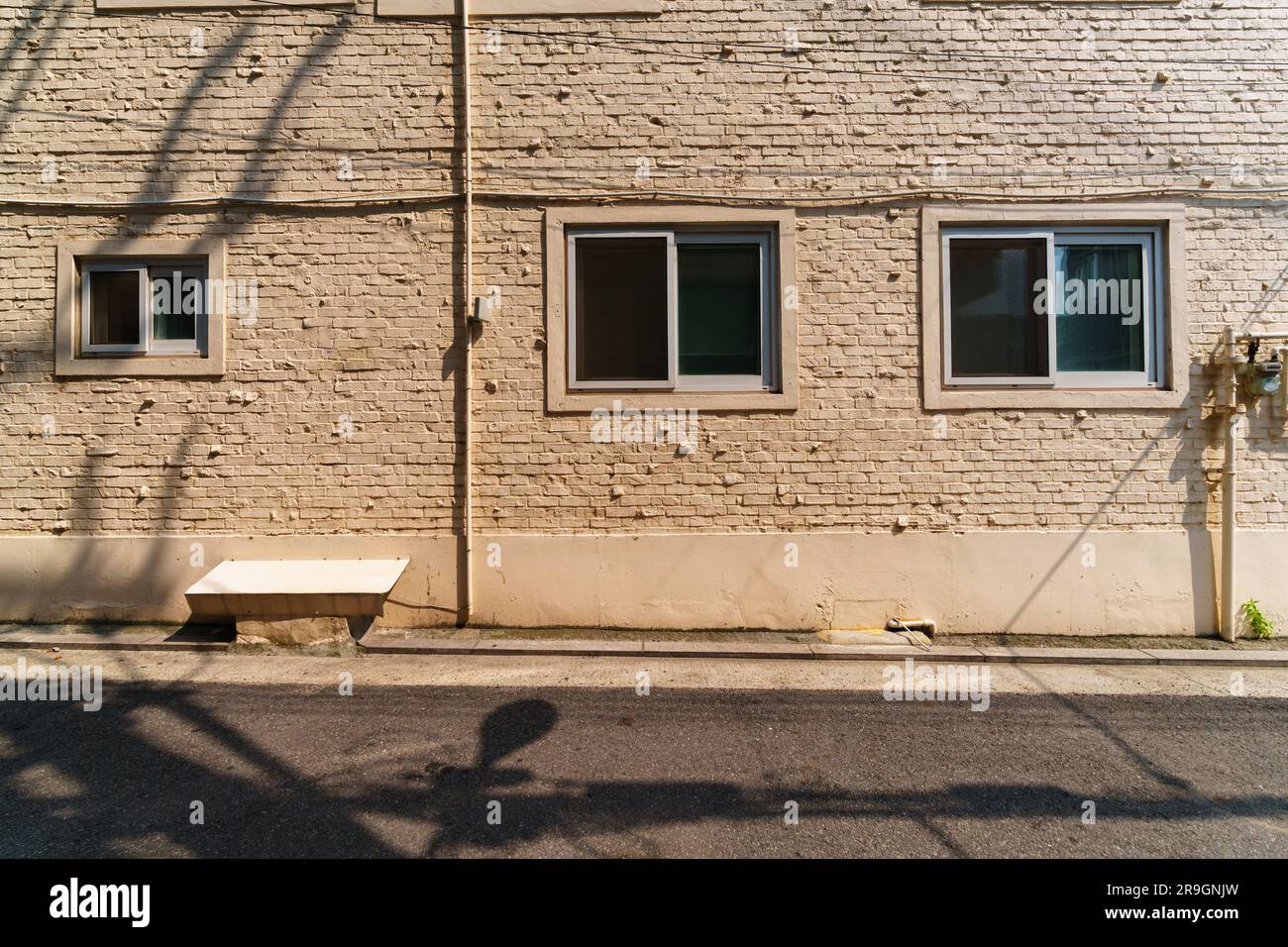 road side view. The wall of an old house adjacent to the road. There is ...