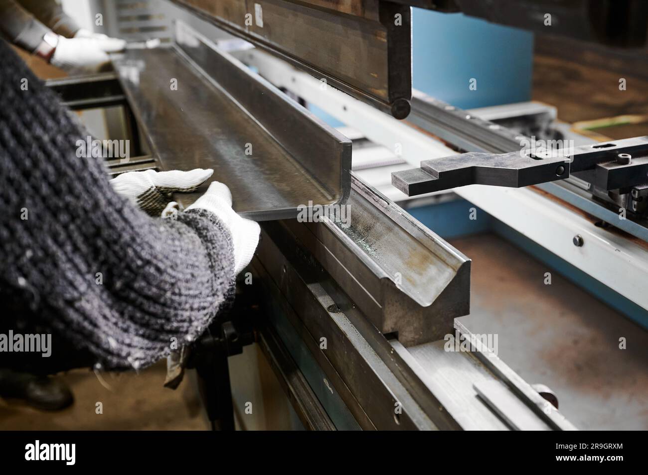 Bending machine operates with heavy metal plate in shop Stock Photo - Alamy