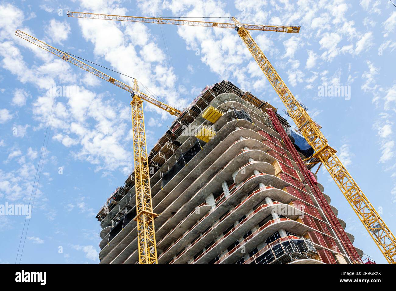High rise condominium building under construction cranes looking upward ...